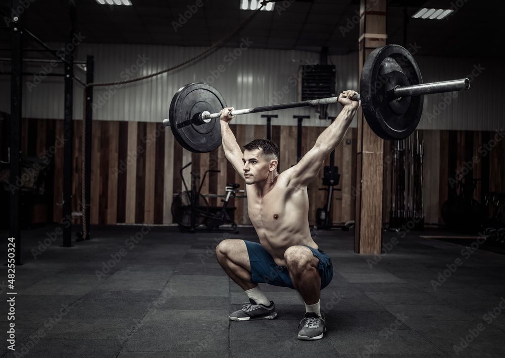 Muscular man practicing heavy barbell overhead at modern health club ...