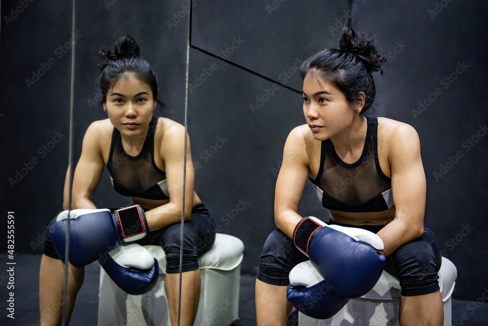 Attractive Asian boxer woman sitting and posing with blue boxing gloves ...