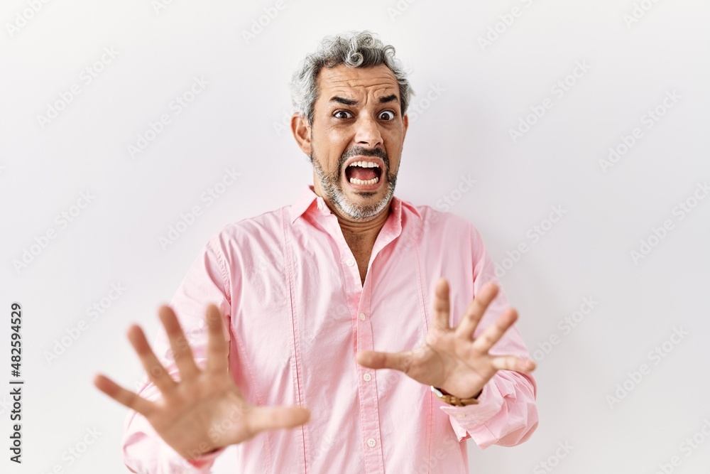 Middle age hispanic man standing over isolated background afraid and ...