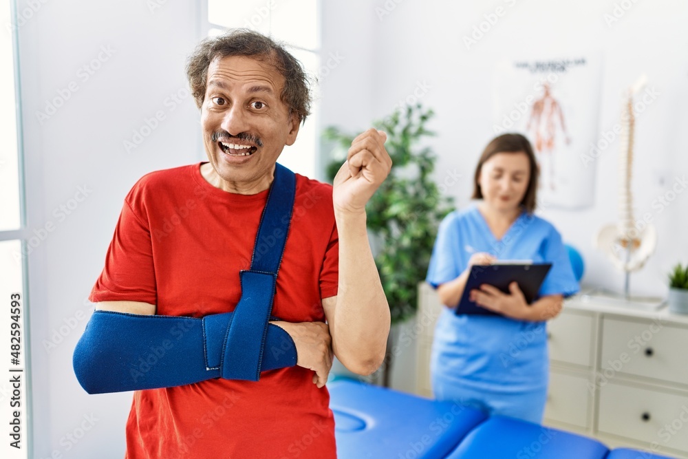 Southeast asian man wearing wearing arm on sling at rehabilitation ...