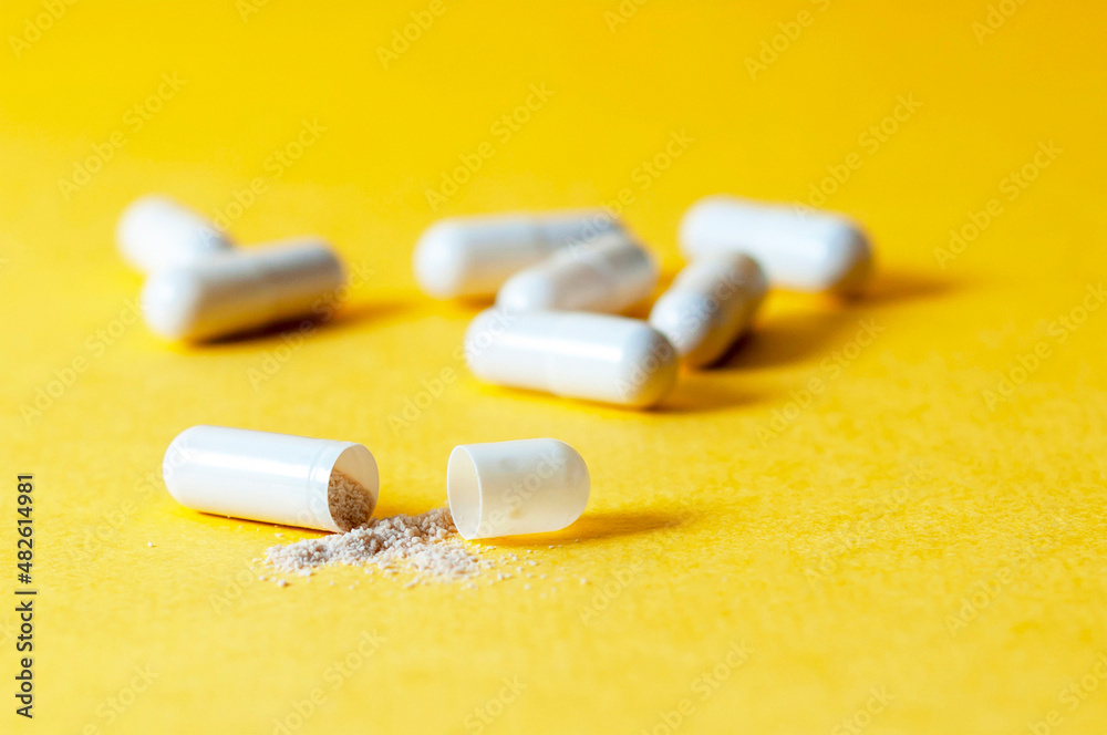 tablets - capsules lie on a yellow background, one capsule is open and ...