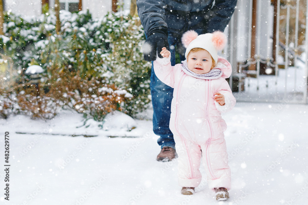 Adorable little baby girl making first steps outdoors in winter through ...