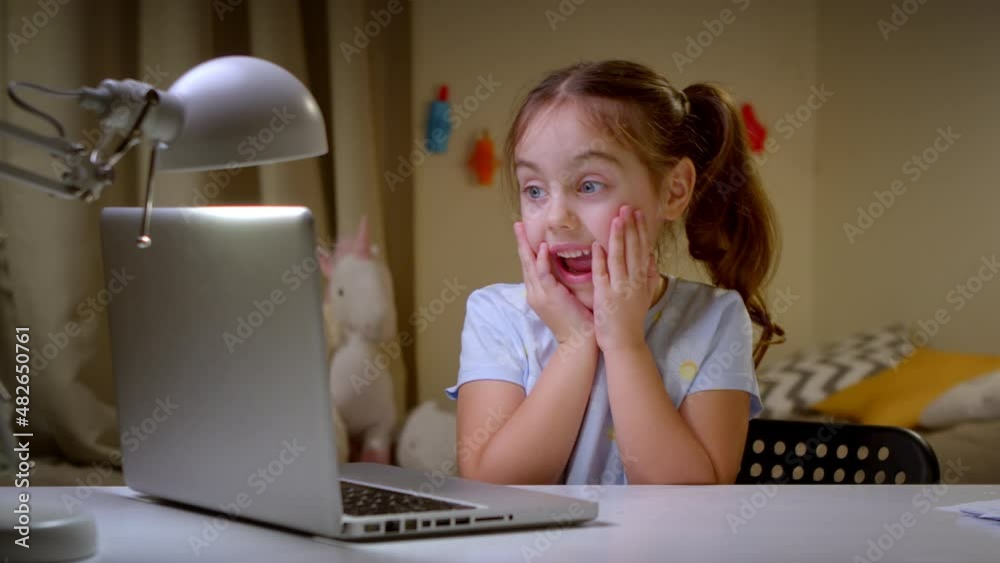 Preschool girl is scared of a horror movie that is watching on a laptop ...
