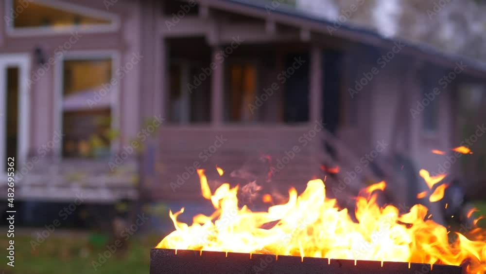 Large flame in grill placed against country house, fire hazard concept ...