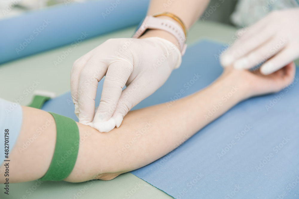 Taking a blood test from a vein in the treatment room. Nurse pricking a ...