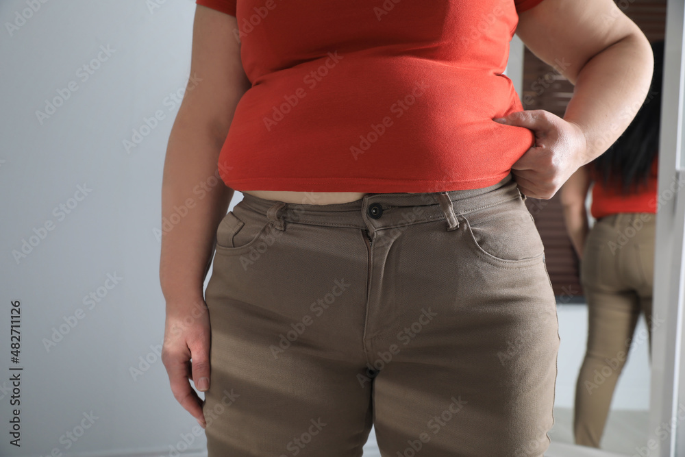 Overweight woman in tight shirt and trousers at home, closeup Stock ...