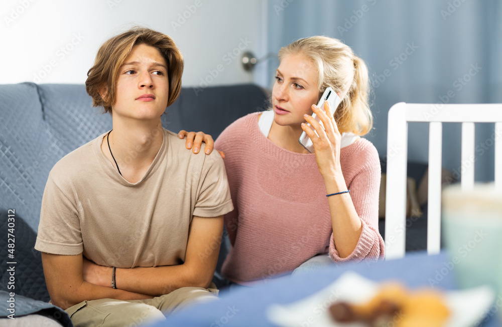 Teenage boy suffering from abdominal pain sitting on sofa at home ...