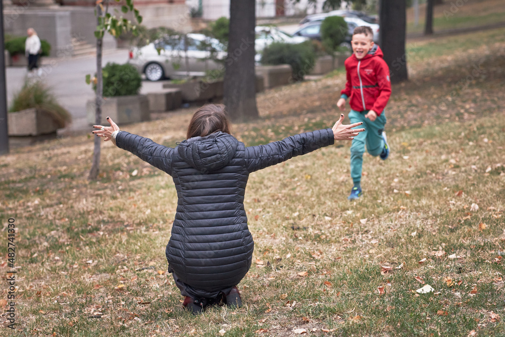 Mom meets her son from the park. joyful child runs into the arms of his ...