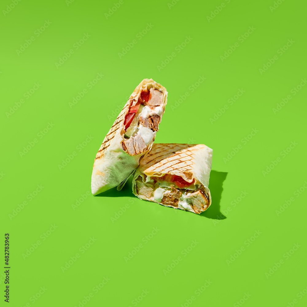 Shawarma with vegetables and meat on green background. Contemporary ...