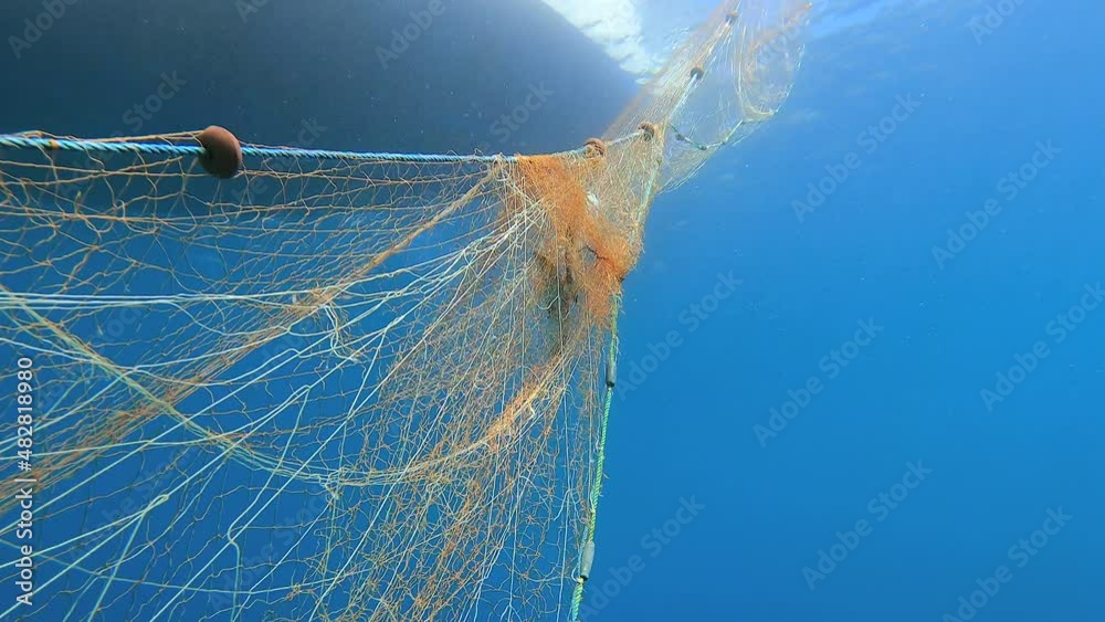 4K.Caught fish in the net hanging from the boat under the sea ...