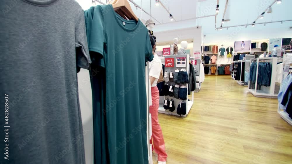 Asian woman wearing medical face mask chooses clothes in a clothing ...
