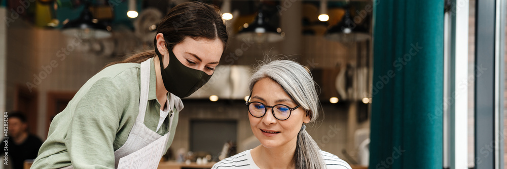 Young waitress woman wearing face mask showing menu to her client Stock ...
