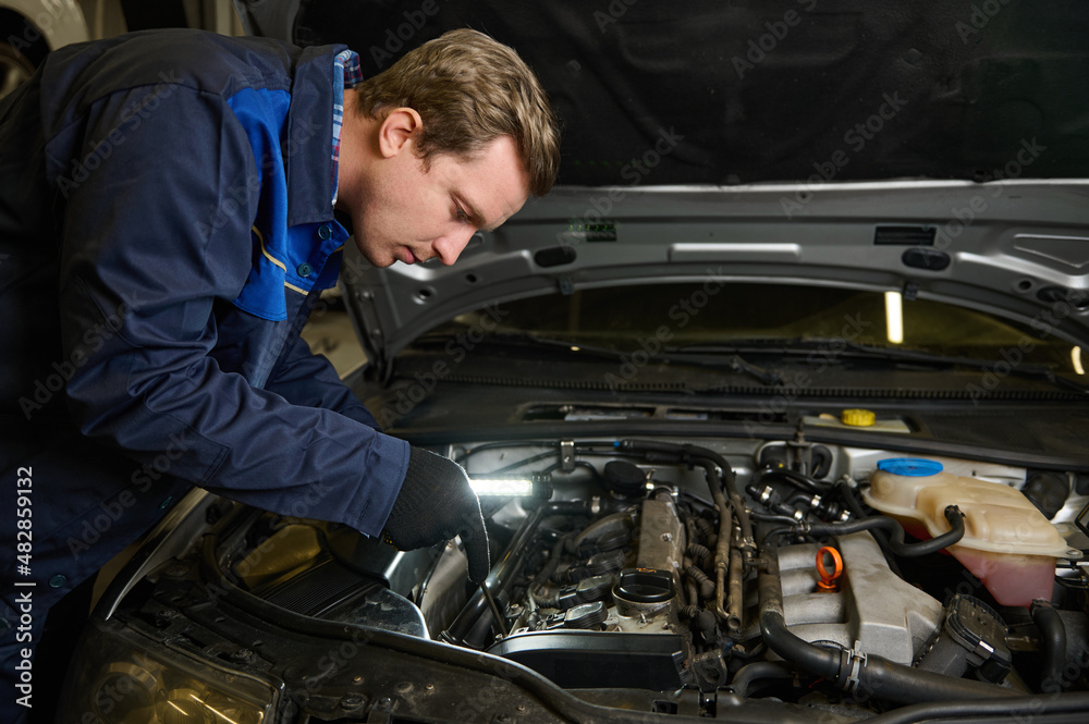 Auto mechanic with a flashlight lamp doing a thorough inspection for ...