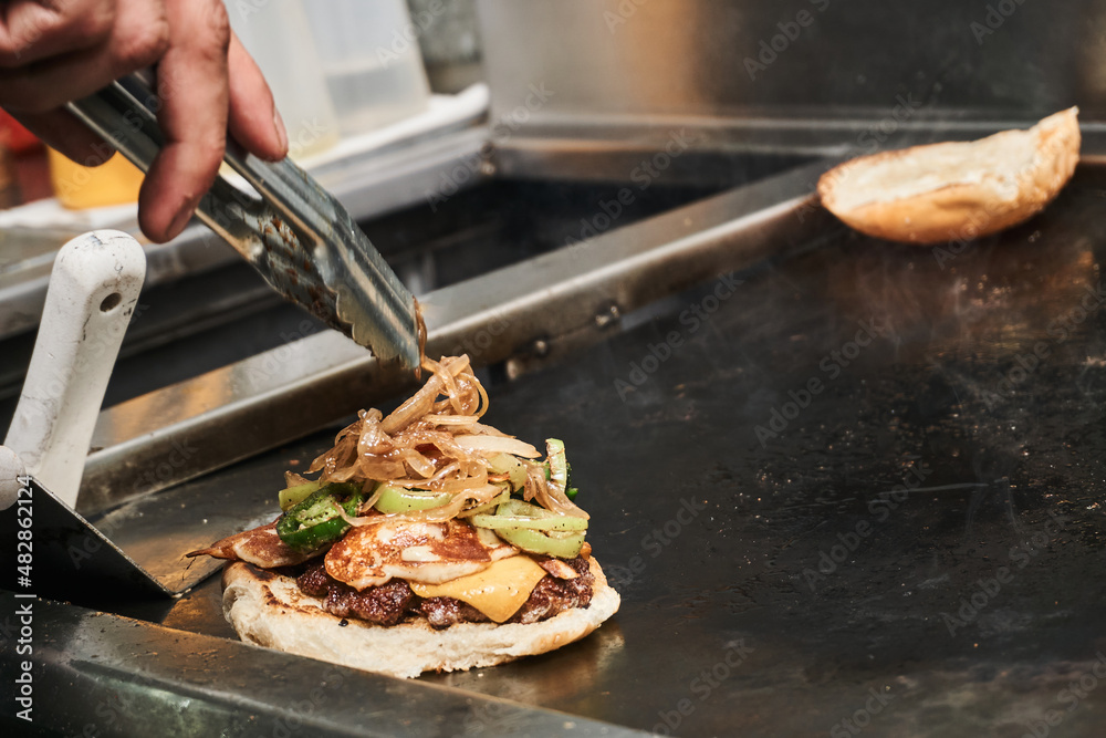 Faceless cook adding ingredient to burger Stock Photo | Adobe Stock