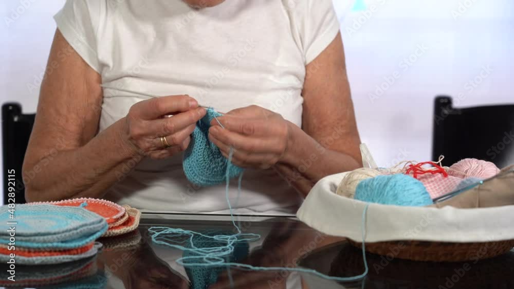 70 year old elderly lady works with crochet and cotton thread to create ...