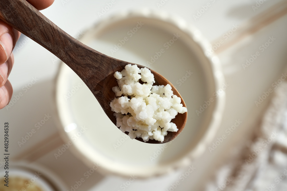 Kefir grains on a spoon - preparation of a fermented beverage, top view ...