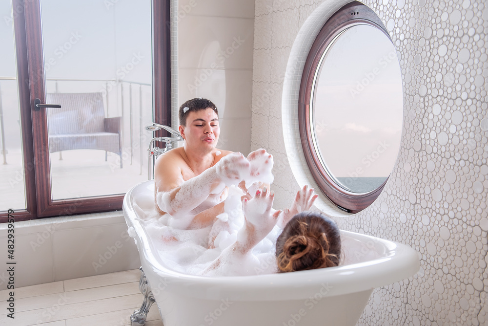 A couple in love fooling around while taking a bubble bath. Millennials ...