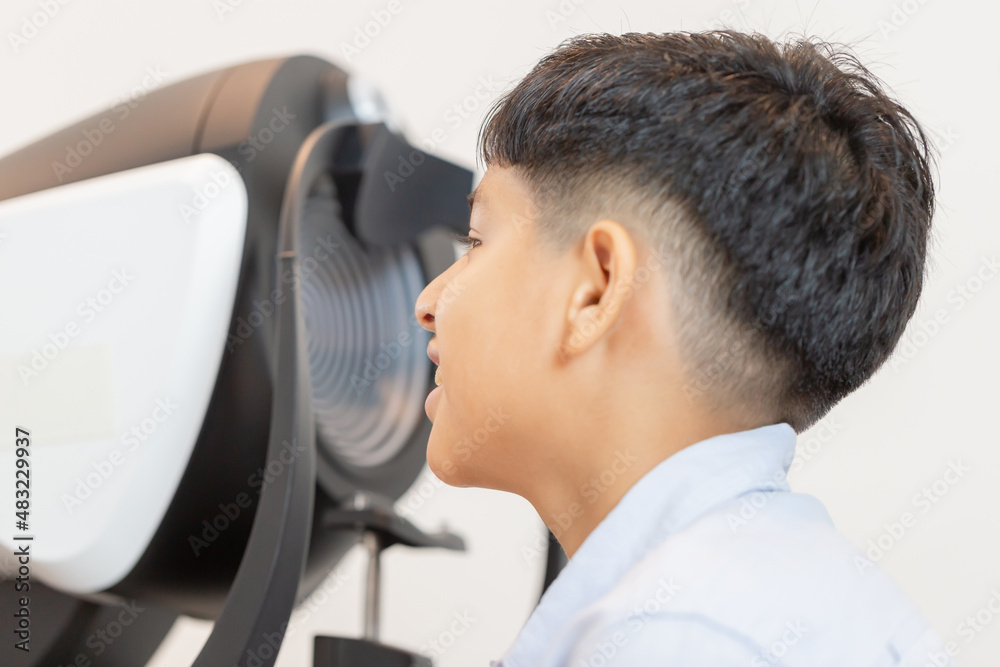 Indian boy doing eye test checking examination with autorefractor in ...
