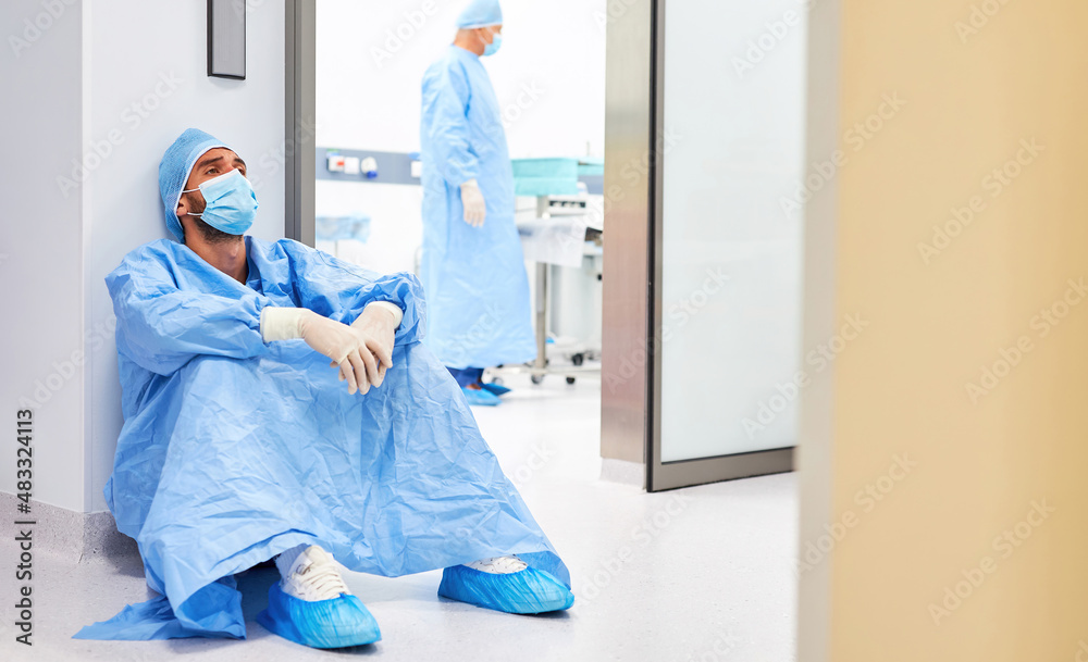 Exhausted surgeon sits on floor in front of the operating room Stock ...