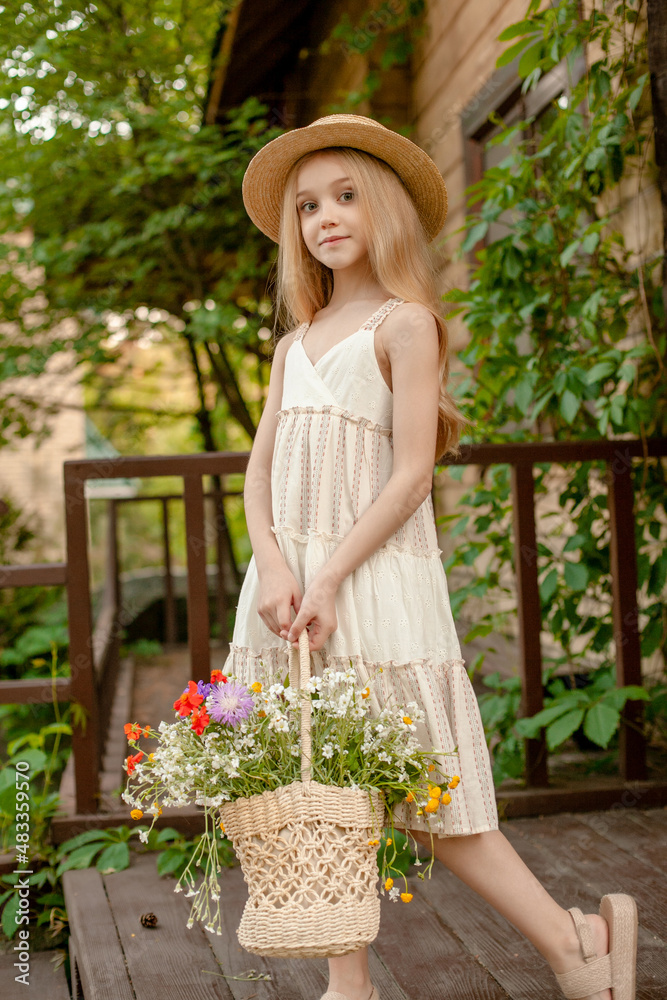 Dreamy tween girl with wildflower in basket standing on doorstep of ...