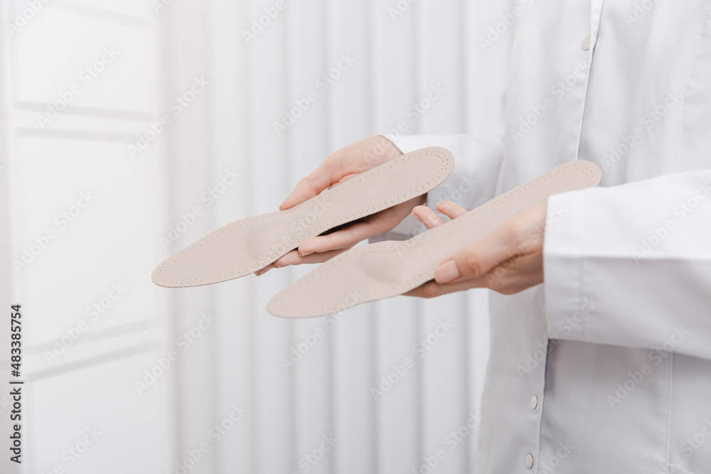 Doctor holding orthopedic insoles in his hands. Orthopedist tests the ...