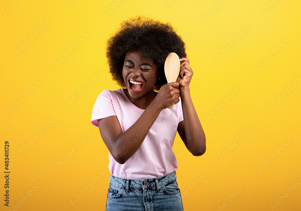 Hair detangling. African american lady brushing tangled hair with ...