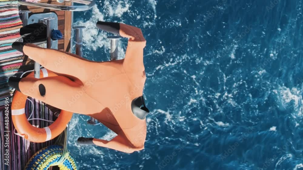 Vertical footage orange diving wet suit hangs dry in sun of sailing ...