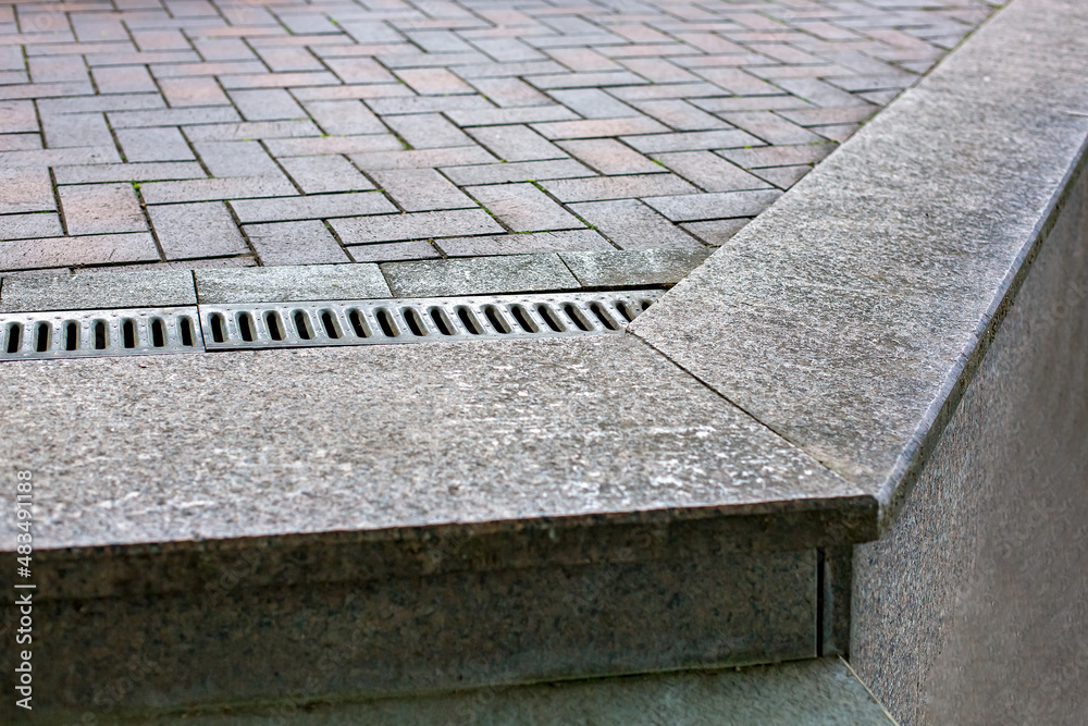 Pavement drainage grate with line iron grill on rectangular stone tile ...