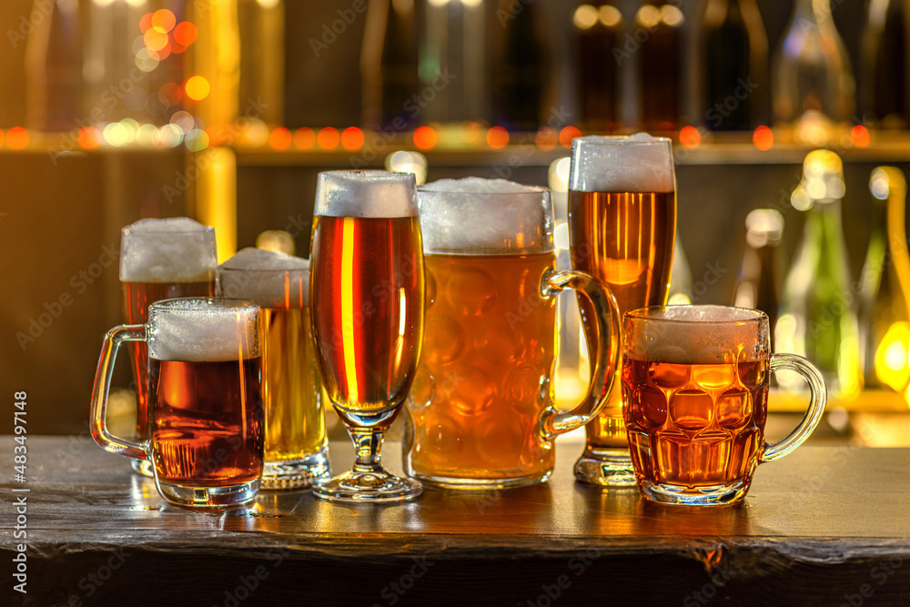 Glass of beer on the bar counter. Jugs, mugs, pints of brew beverage ...