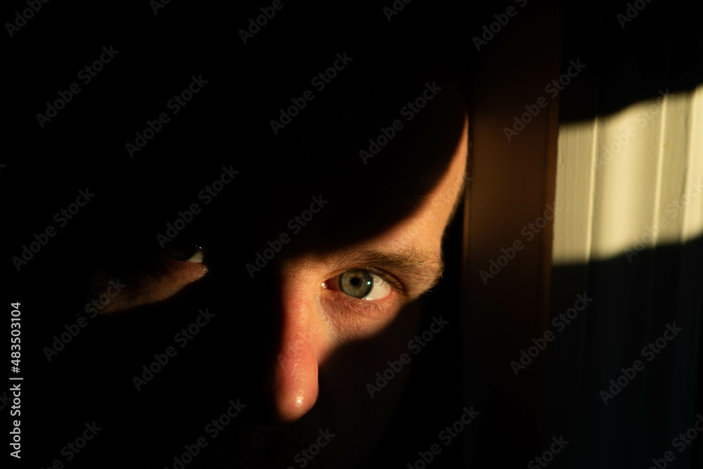 Man in shadow only his eyes are showing, illuminated with natural light. Stock Photo | Adobe Stock