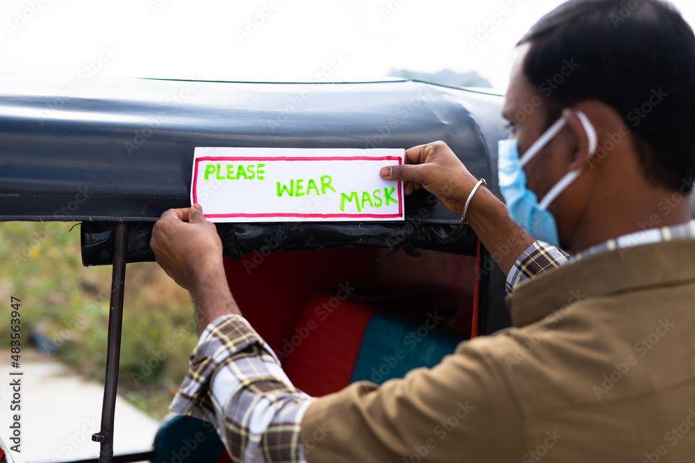 Focus on notice, Auto driver with medical face mask pasting Please wear ...