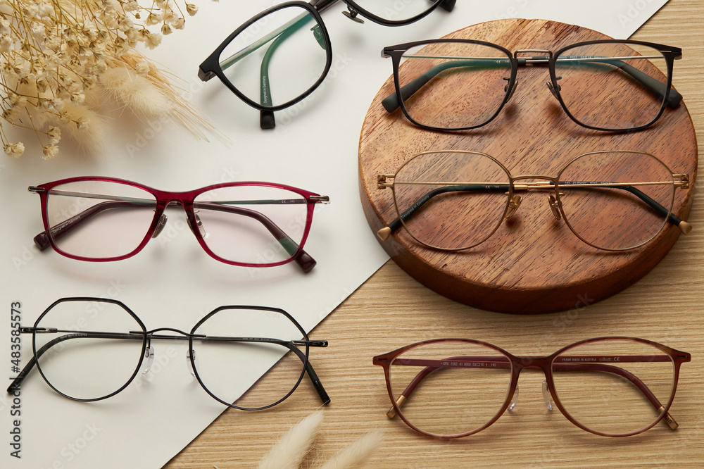 A photo of eyeglasses of different frames colors and shapes with wooden ...