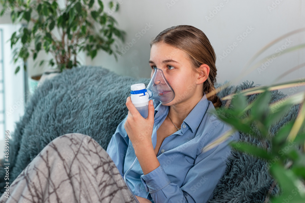 Teenage girl makes inhalation with a nebulizer equipment. Sick child ...
