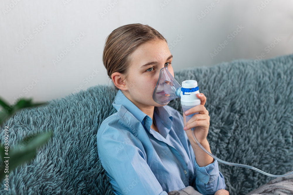 Teenage girl makes inhalation with a nebulizer equipment. Sick child ...