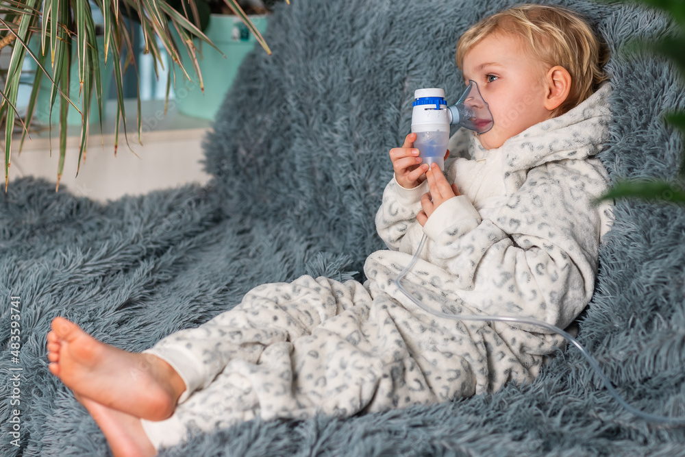Cute baby boy makes inhalation with a nebulizer equipment. Sick child ...