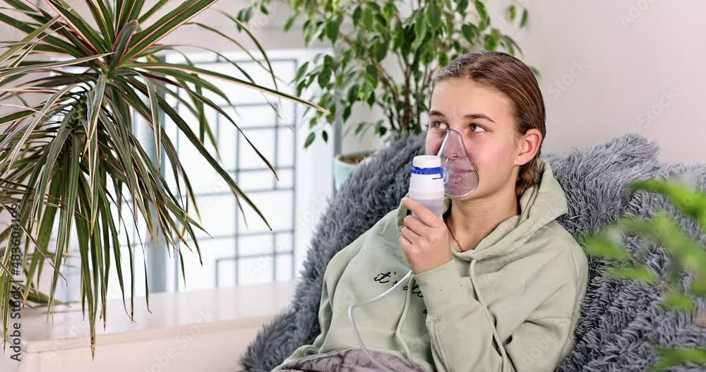 Teenage girl makes inhalation with a nebulizer equipment. Sick child ...