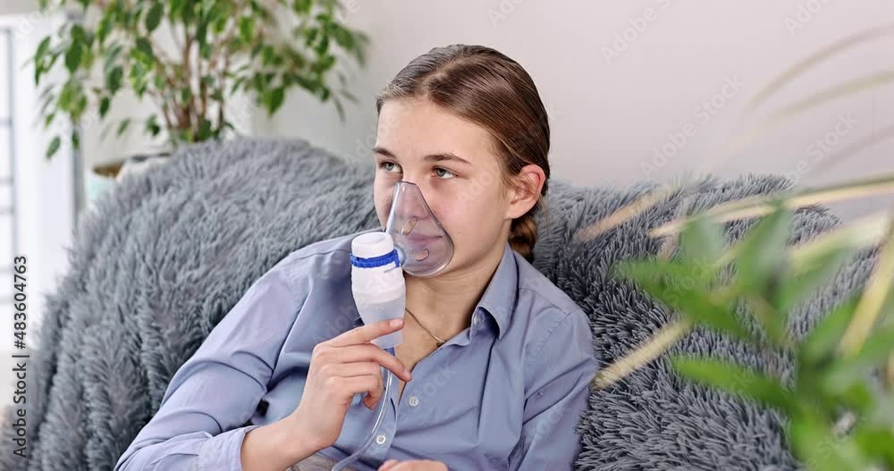 Teenage girl makes inhalation with a nebulizer equipment. Sick child ...