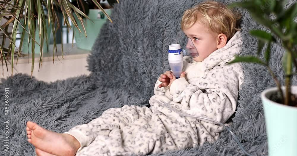 Cute baby boy makes inhalation with a nebulizer equipment. Sick child ...