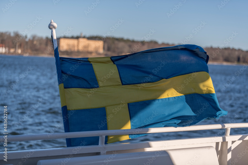 Swedish flag at the aft of a commuting boat with skyline of the island ...
