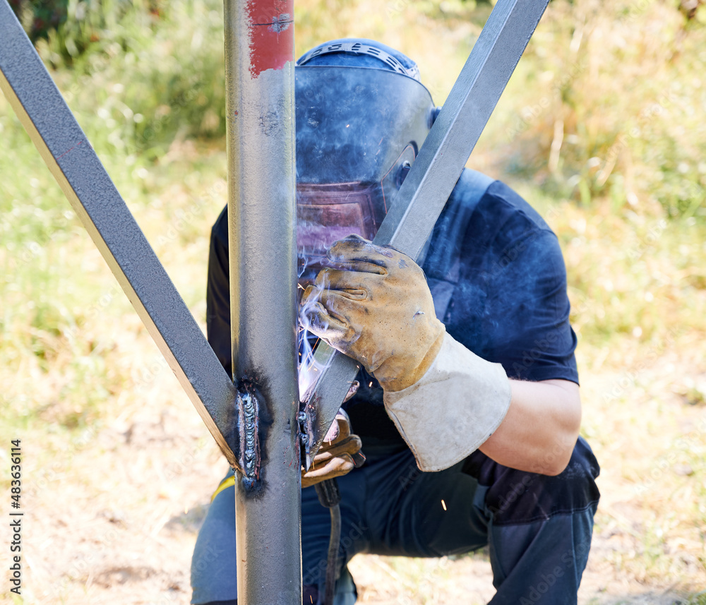 Welder welding metal beam with welding machine for installing solar ...