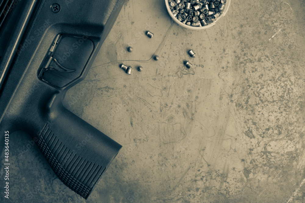 pneumatic shooting.an air rifle and bullets on a steel table. A black ...