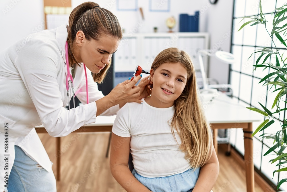 Woman and girl doctor and patient examining ear using otoscope at ...