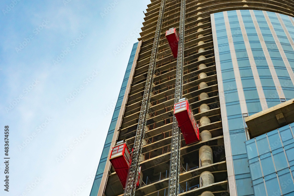 Building under construction with temporary elevators. Red temporary ...