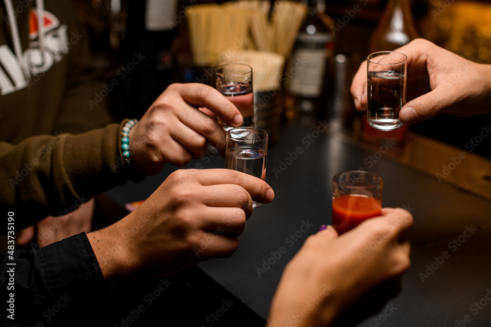 Four young people toasting with mexican tequila shots and tomato juice ...