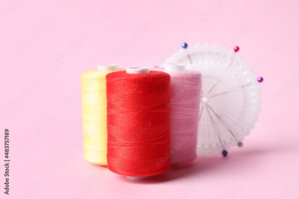 Multicolored sewing thread spools and pins on color background Stock ...