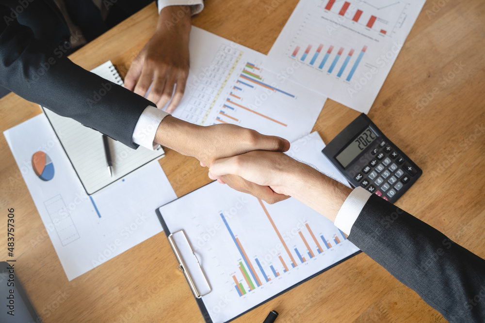 Above view hand of client and banker shaking hands on the meeting table ...