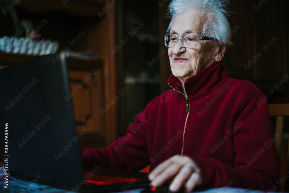 Old woman alone in her room using the computer. Grandmother using ...