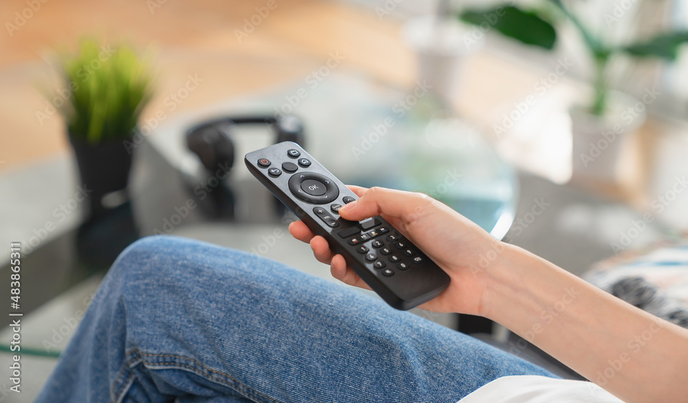 Woman sitting on sofa and hand holding TV remote control with press the ...