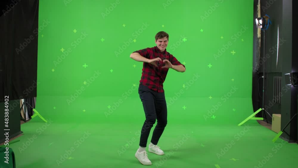 A young man dancing on a green screen background. Attractive guy making ...