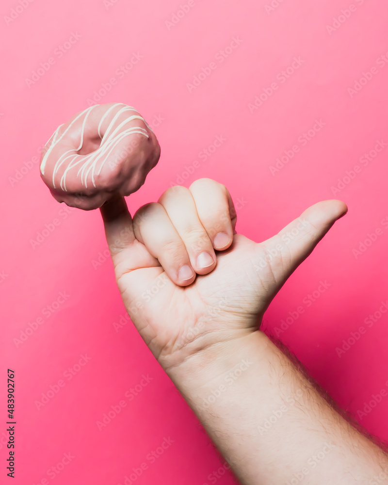 Shaka signal with a donut in a little finger Stock Photo | Adobe Stock